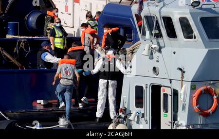 Ein Schiff der Border Force bringt eine Gruppe von Menschen, die als ...