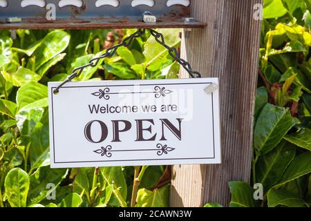 Wir sind offen Schild hängen auf bewaldeten Pfosten Stockfotografie - Alamy