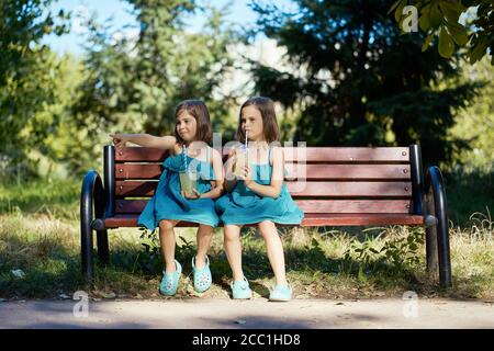 Zwei Mädchen sitzen auf einer Bank im park Stockfotografie - Alamy
