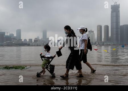 Bürger gehen entlang der wasserdurchflussten Straße in der Stadt Wuhan ...