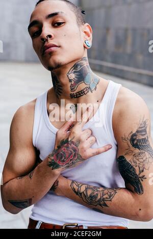 Junger lateinamerikanischer Mann mit Tattoos in Business-Anzug und Krawatte mit der Faust, um zu ...