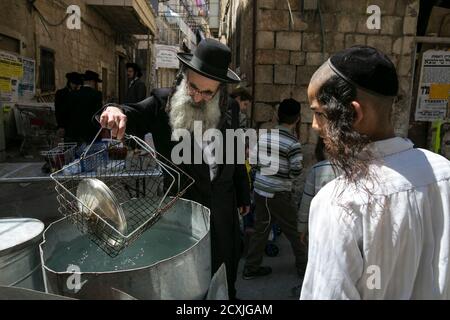 An ultra-Orthodox Jewish man dips cooking utensils in boiling water to ...