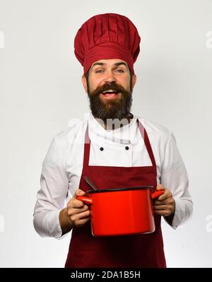 Kochen Sie mit aufgeregt Gesicht in burgunderrot Uniform sitzt am Tisch ...