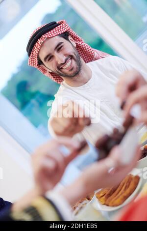 Muslimische Familie, die Iftar zum Essen trinkt, um das Festmahl zu unterbrechen. Traditionelles ...