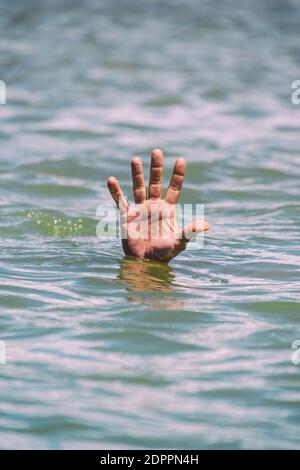 Die Hand des Mannes ragt aus dem Wasser in der Mitte des Ozeans, eine ...
