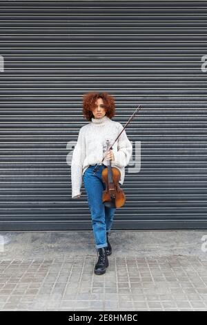 Ganzkörper emotionslos Rothaarige Musikerin im lässigen Outfit stehend ...