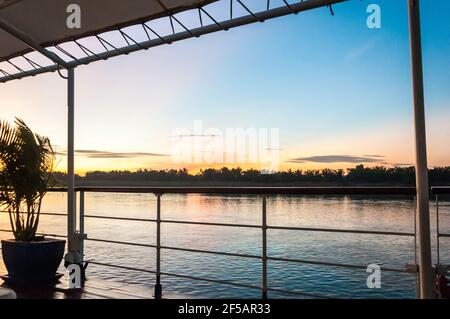 Abendstimmung auf dem Mekong. Blick von einem Flussschiff mit Geländer ...
