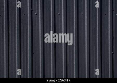 Schwarzes Wellblech, das als Fassade eines Lagers oder einer Fabrik ...