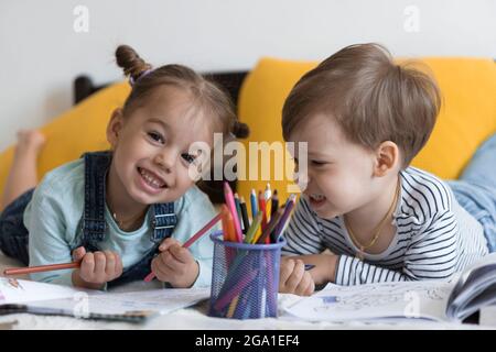 Smart lächelnd Vorschool Kleinkind Kinder Junge und Mädchen zeichnen mit Bleistiften liegen auf ...