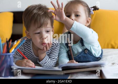 Smart lächelnd Vorschool Kleinkind Kinder Junge und Mädchen zeichnen mit Bleistiften liegen auf ...