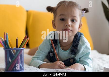 Smart lächelnd Vorschool Kleinkind Kinder Junge und Mädchen zeichnen mit Bleistiften liegen auf ...