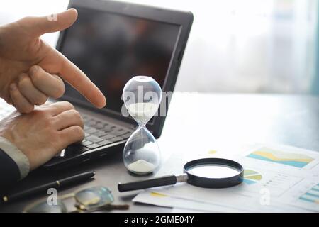 Arbeitszeit symbolisiert eine Sanduhr. Schreibtisch mit ...