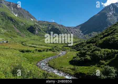 Alpenlandschaft entlang der Nufenenpassstraße mit einer Windturbine ...