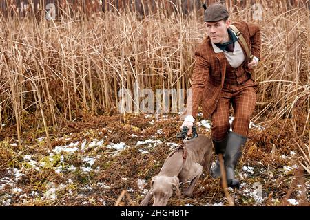 Grauer Hund führt den Mann des Besitzers Mann Jäger zur Seite, leitet ...