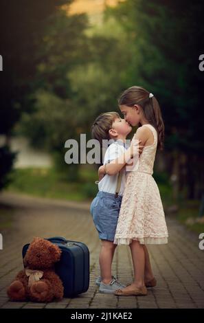 Zwei kleine Kinder umarmen und küssen sich im Sommergarten. Kinder ...