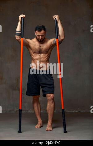 Ein Ninja-Mann hält sich an einen Kampfstock und greift Nahaufnahmen ...