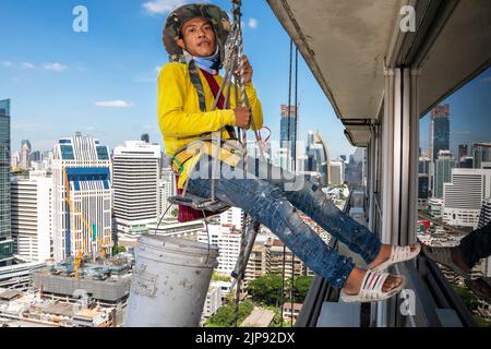 Thailändischer Arbeiter, der den Bosun Chair zur Reparatur des ...