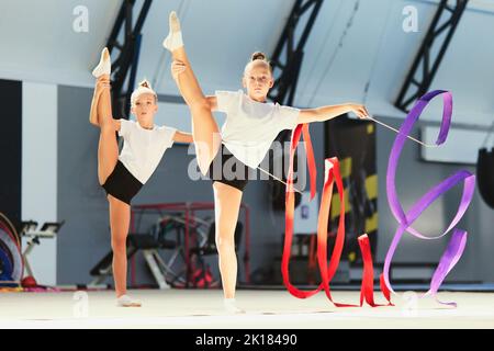 Zwei kleine Mädchen, weibliche rhythmische Turnerin Training mit bunten ...