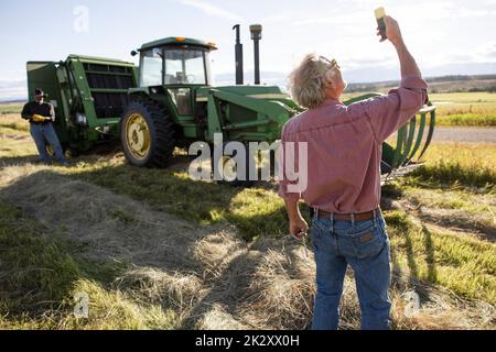 Älterer männlicher Landwirt, der versucht, einen Smartphone-Empfang auf ...