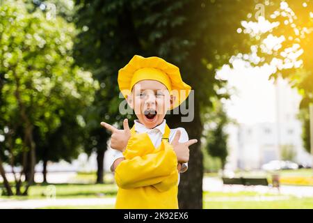 Zeigt richtig. Schöner Koch Kind in gelben Köchhut und Schürze gelbe ...