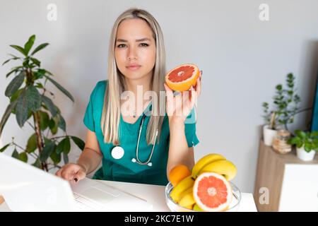 Ernährungsberaterin mit Früchten, die an ihrem Schreibtisch arbeiteten ...