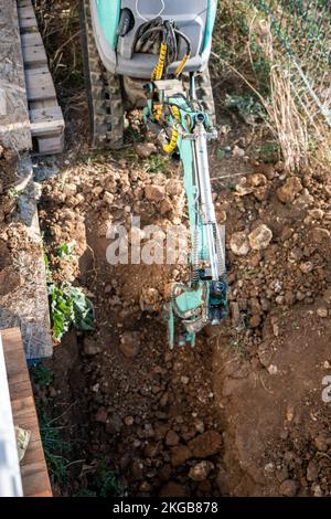 Minibagger gräbt einen Graben, um Rohre zu verlegen. Nahaufnahme eines ...