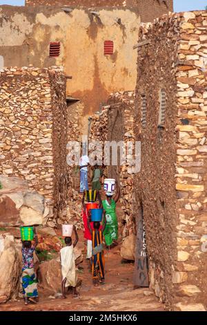Eine Gruppe afrikanischer Kinder, die Wasser zu ihrem Haus ...
