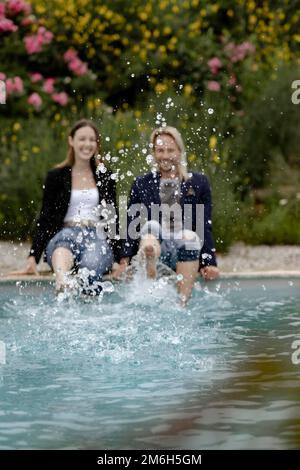 Ein Paar sitzt am Rand des Pools und spritzt Wasser Stockfotografie - Alamy