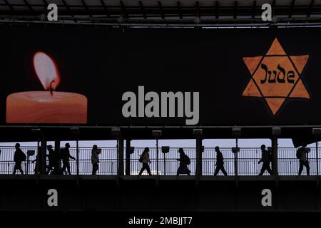 People walk along a bridge lit with a billboard showing a yellow Star ...