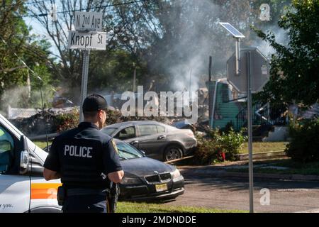 A Manville Police Officer stands guard near the remains of a house that ...