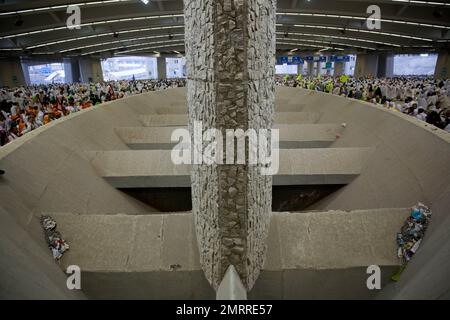 Muslim pilgrims cast stones at a pillar, symbolizing the stoning of ...
