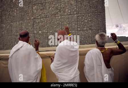 Muslim pilgrims cast stones at a pillar, symbolizing the stoning of ...
