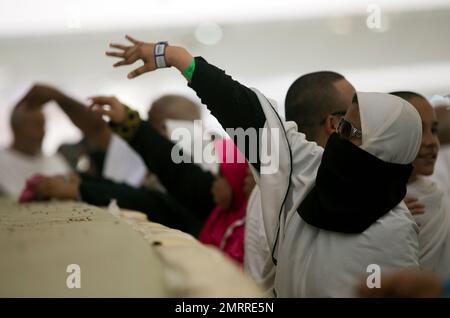 Muslim pilgrims cast stones at a pillar, symbolizing the stoning of ...