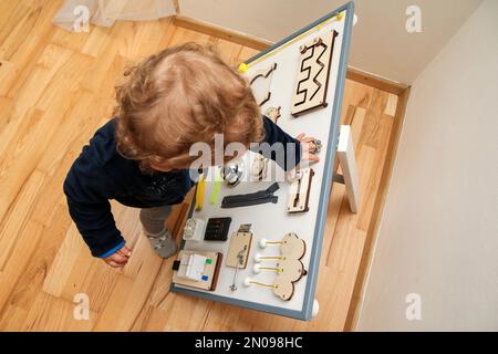 Das kleine Kind spielt mit dem Spielbrett, um neue Erfahrungen zu ...