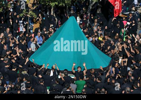 Iranian mourners symbolically beat themselves as they circle a burning ...