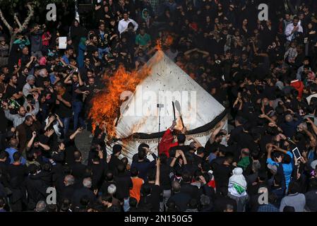 Iranian mourners symbolically beat themselves as they circle a burning ...