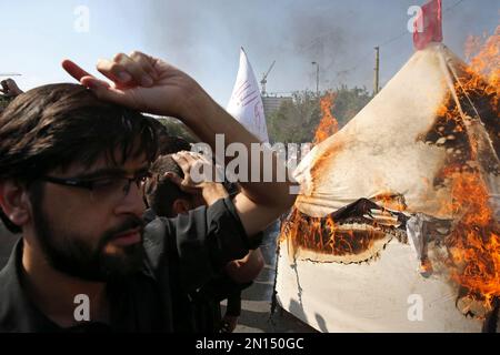 Iranian mourners symbolically beat themselves as they circle a burning ...
