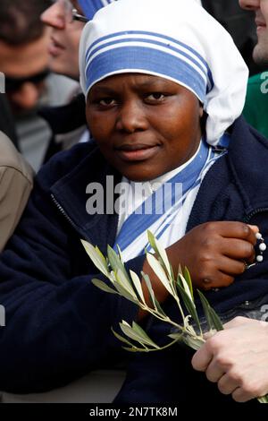 A nun holds a branch of an Olive tree during an open-air Palm Sunday ...