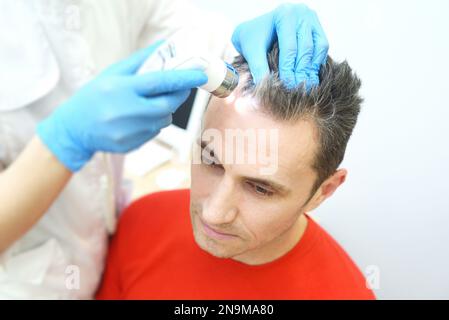 Ein Kosmetologe-Trichologe diagnostiziert den Zustand des Haares eines ...