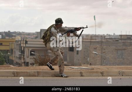 A Libyan rebel fighter fires his machine gun toward loyalist positions ...