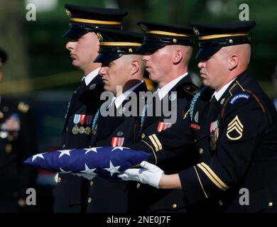 An Army honor guard passes the folded flag that draped the coffin of ...