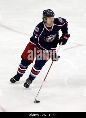 Columbus Blue Jackets' Mike Commodore, left, knocks the puck away from ...