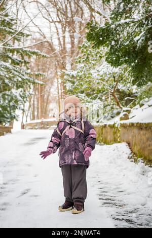 Schnee fällt und kleines Mädchen, Zeitlupe. Fröhliches Kind freut sich ...