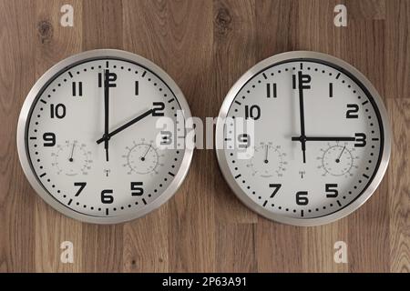 Zwei Uhren, eine auf zwei Uhr, die andere auf drei Uhr. Tulpen liegen ...