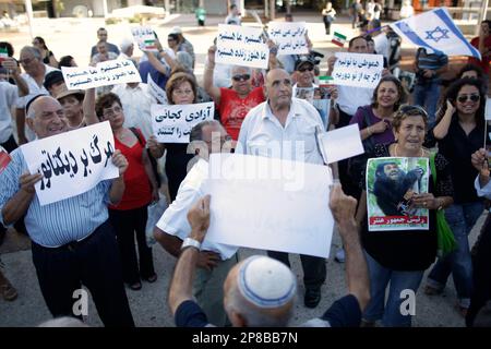 Israelis of Iranian origin hold signs, a flag and images purporting to ...