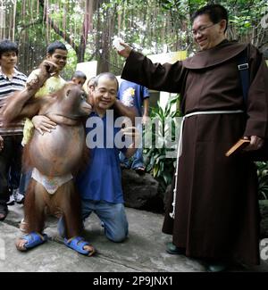 A Filipino Catholic priest sprinkles holy water on palm fronds outside ...