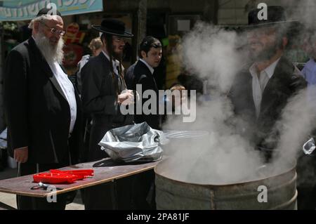 An ultra-Orthodox Jewish man dips cooking utensils in boiling water to ...