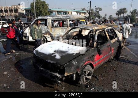 Iraqis look at cars destroyed in a car bomb explosion in the New ...