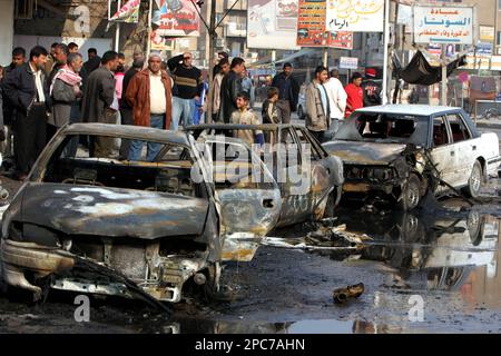 Iraqis look at cars destroyed in a car bomb explosion in the New ...