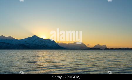 Abendrot mit einem hellen Sonnenstrahl über den verschneiten Bergen von ...